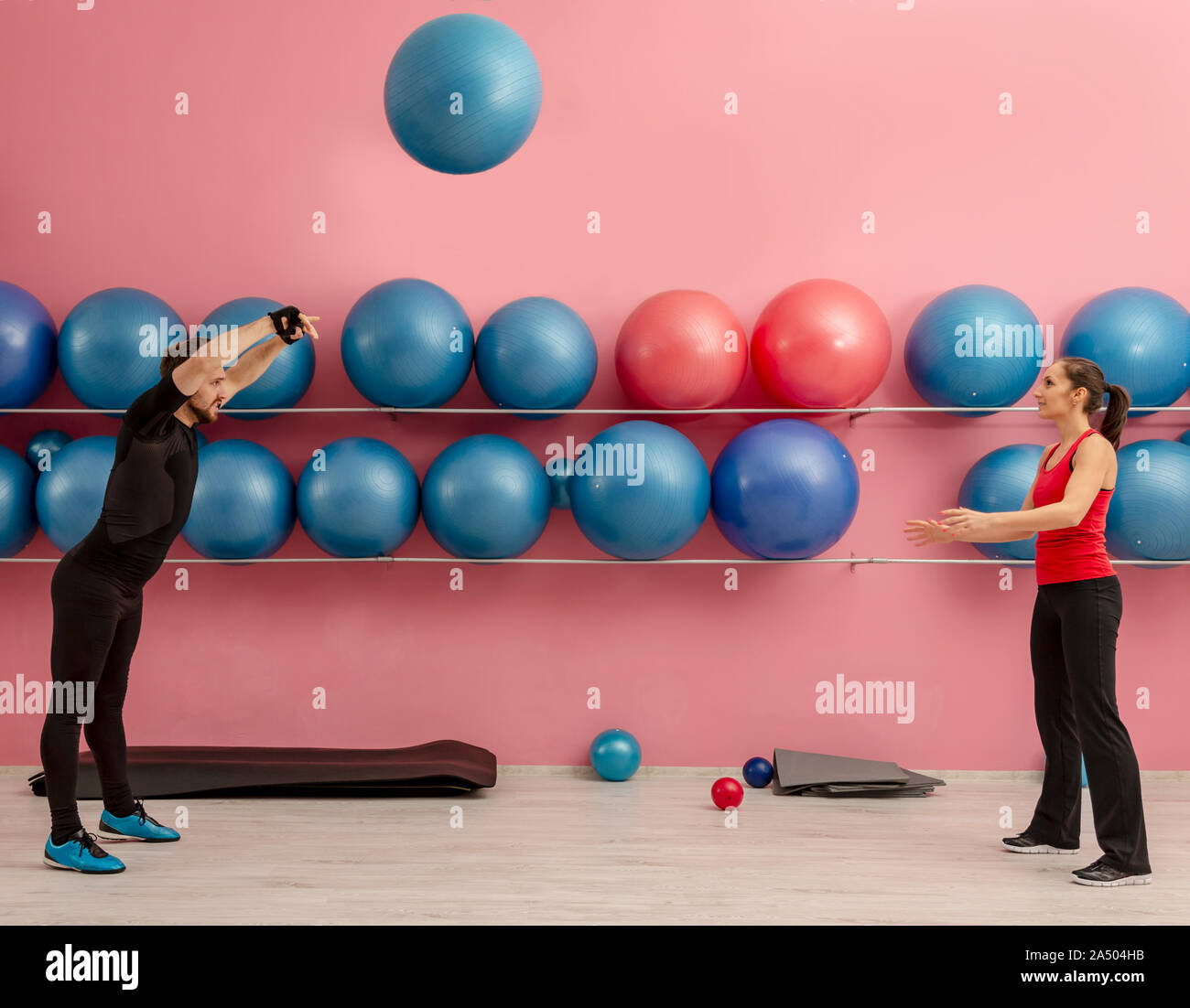 Young couple doing exercises with a ball in a gym Stock Photo - Alamy