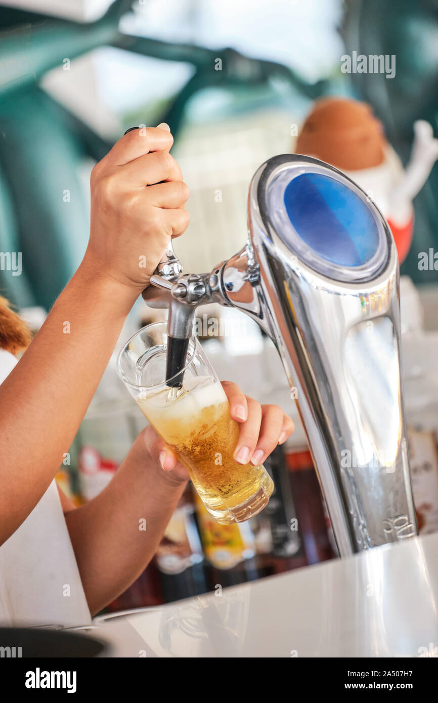 We meet oktoberfest. Hand of bartender pouring a large lager beer in ...