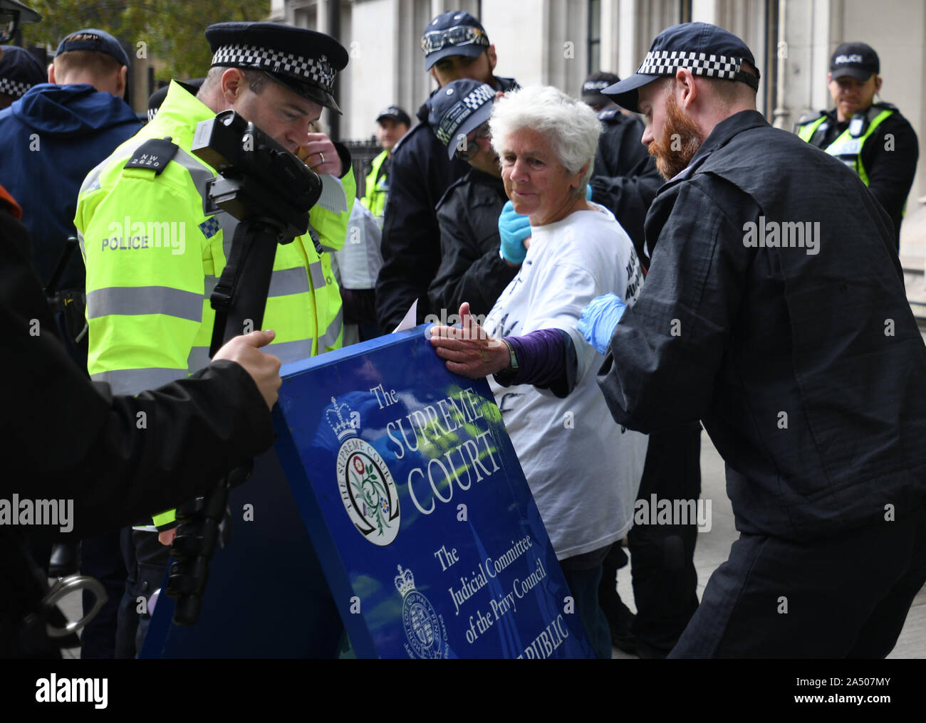 A protester who has glued herself to a sign outside the Supreme Court ...