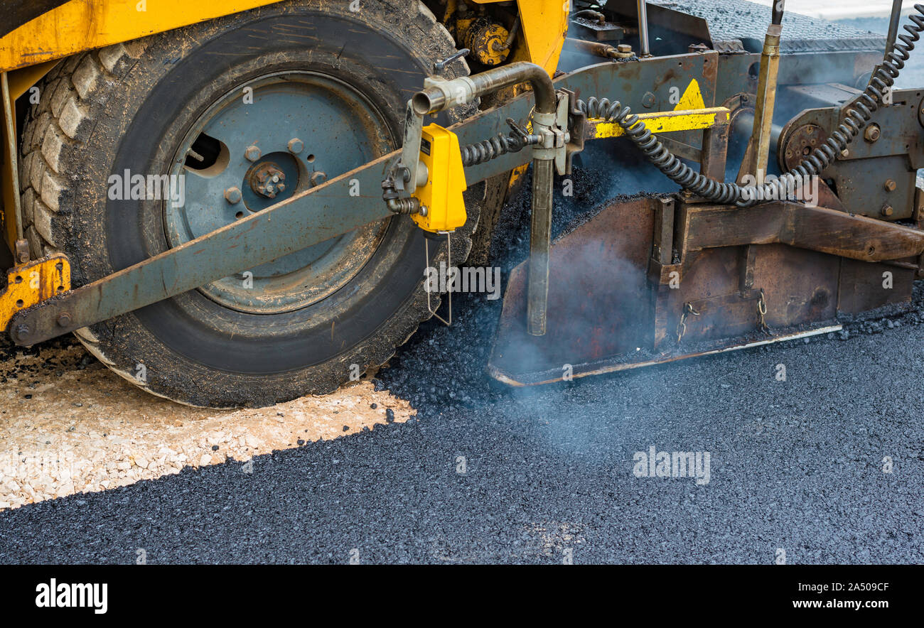 Worker regulate tracked paver laying asphalt heated to temperatures ...
