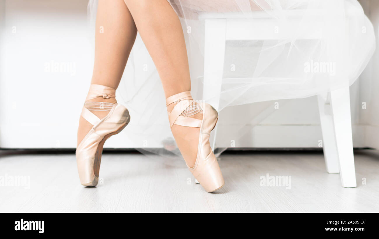 Close-up of dancing legs of ballerina wearing white pointe on a white ...