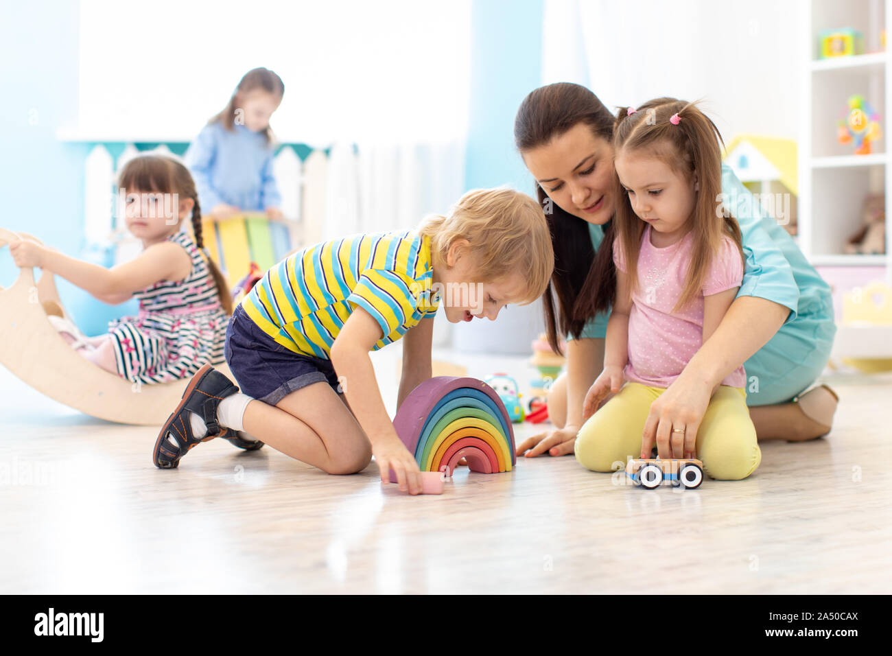 Children group playing in kindergarten. Kids with teacher in class ...