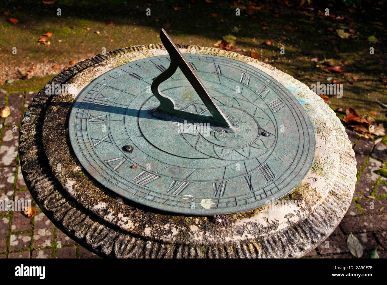 Stone and metal garden sundial on a mottled brick garden path Stock ...