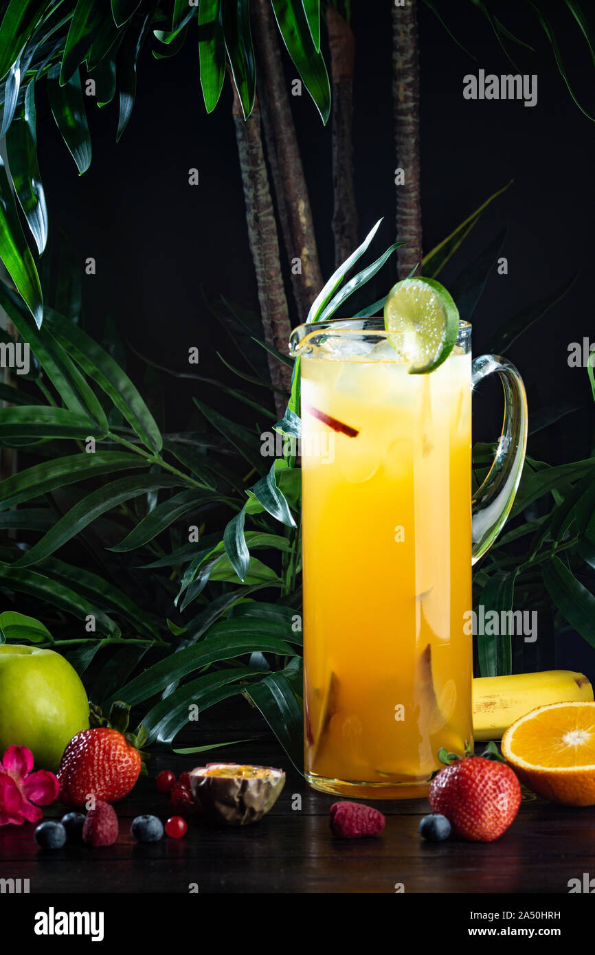 pineapple mango cocktail in a jug on a dark background with fruits ...