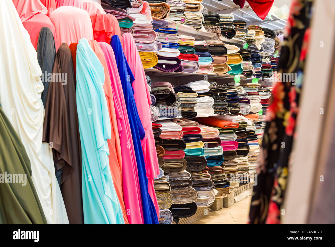 Rolls of fabric and textiles in a factory shop. Multi different colors ...