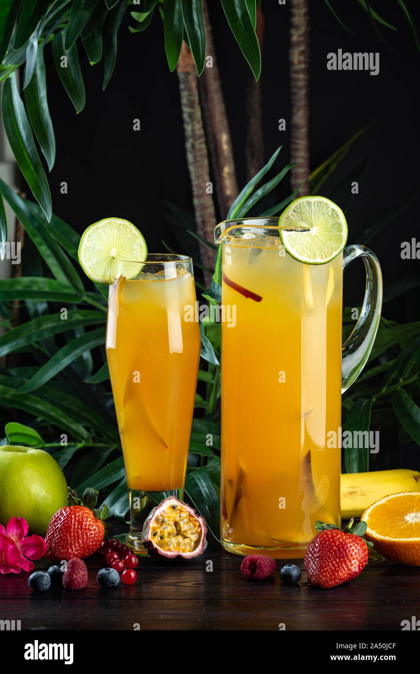 pineapple mango cocktail in a jug and glass on a dark background with ...
