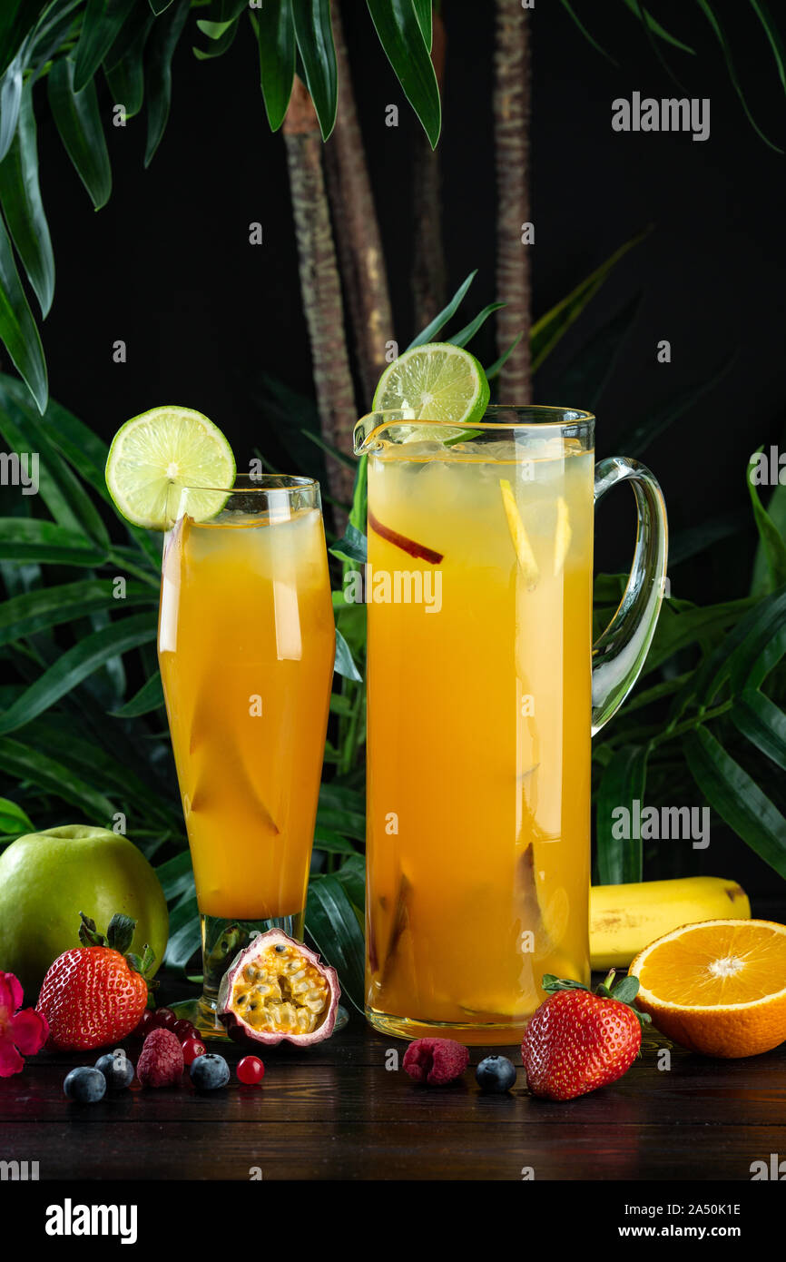 pineapple mango cocktail in a jug and glass on a dark background with ...