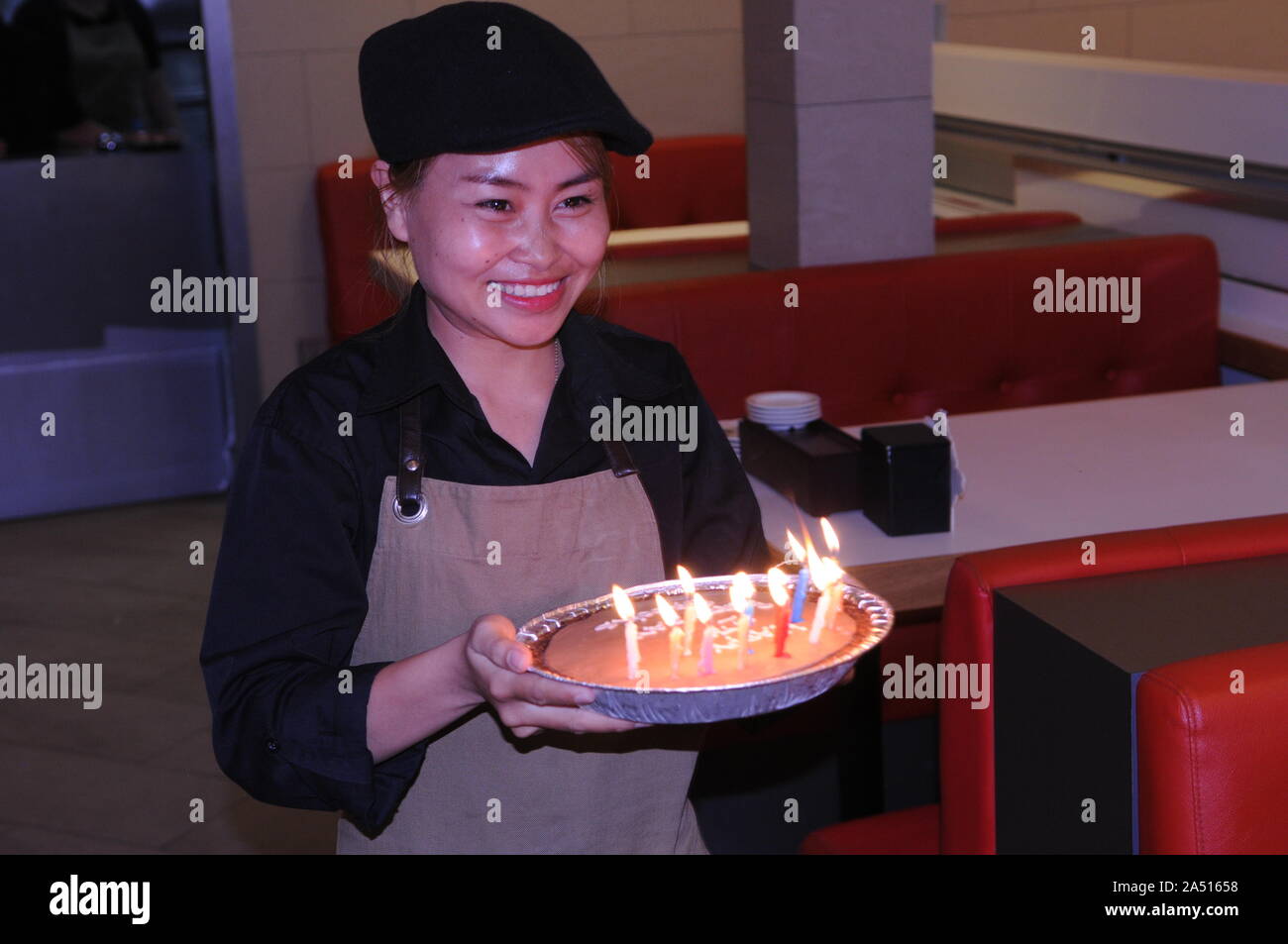 Cambodian waitress brings out a candlelit birthday cake at a restaurant ...
