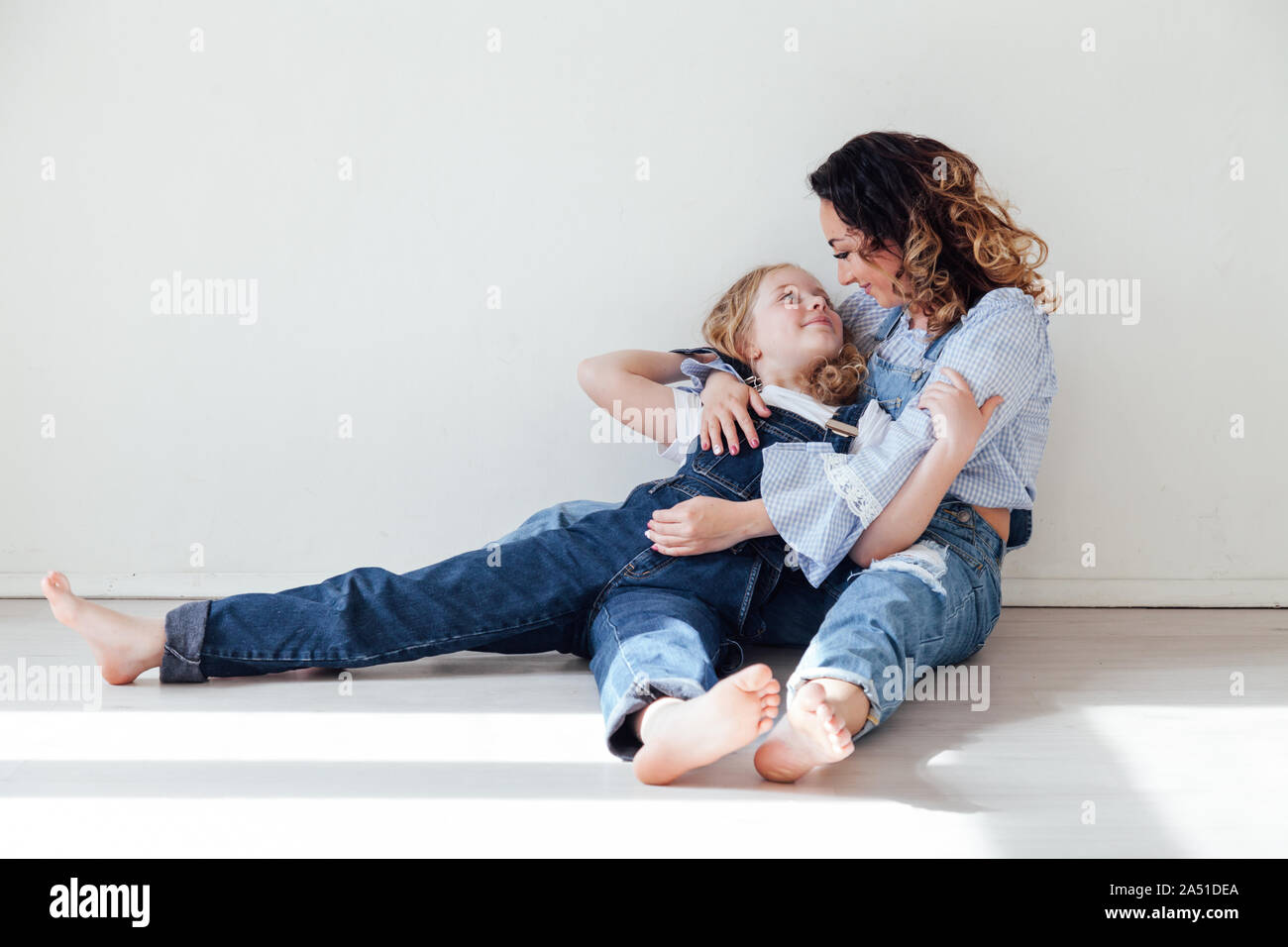 Mom and daughter in jeans cuddle laughing Stock Photo - Alamy