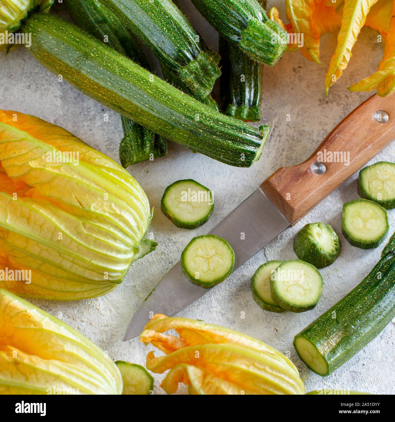Young Zucchini With Flowers with a knife close up Stock Photo - Alamy