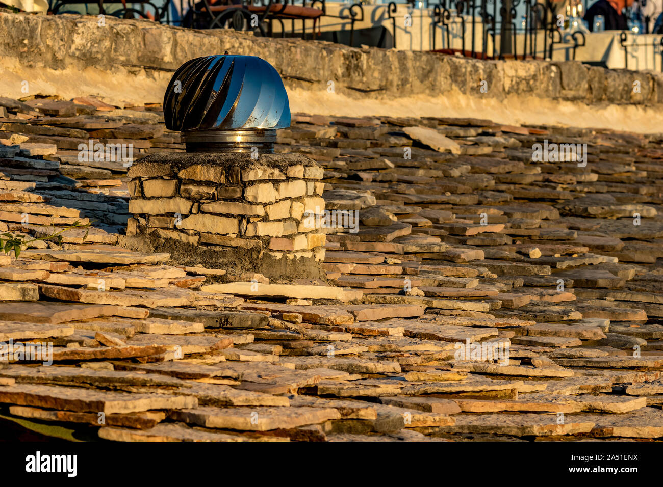 Rotating metallic with blue shades spinner chimney vent on stone tiled ...