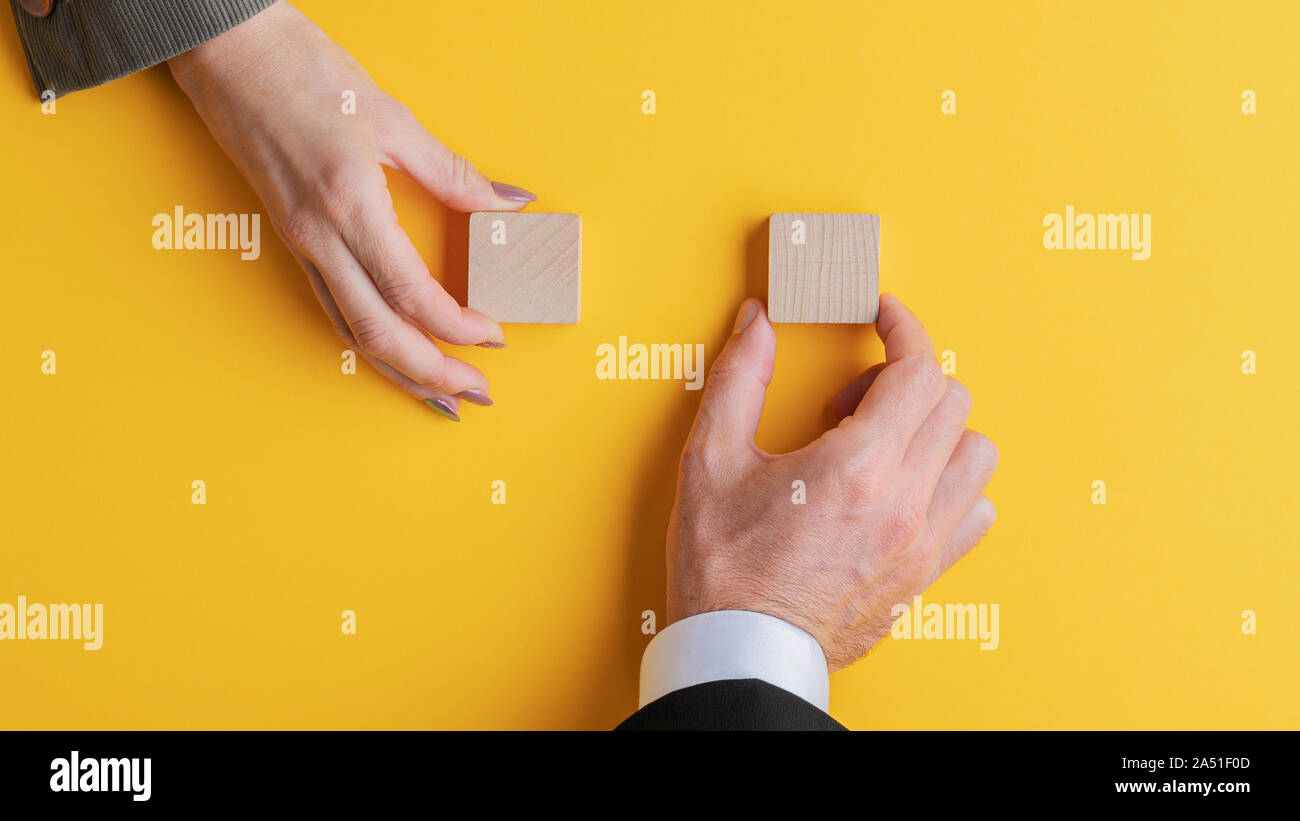 Male and female hand placing blank wooden blocks on bright yellow ...