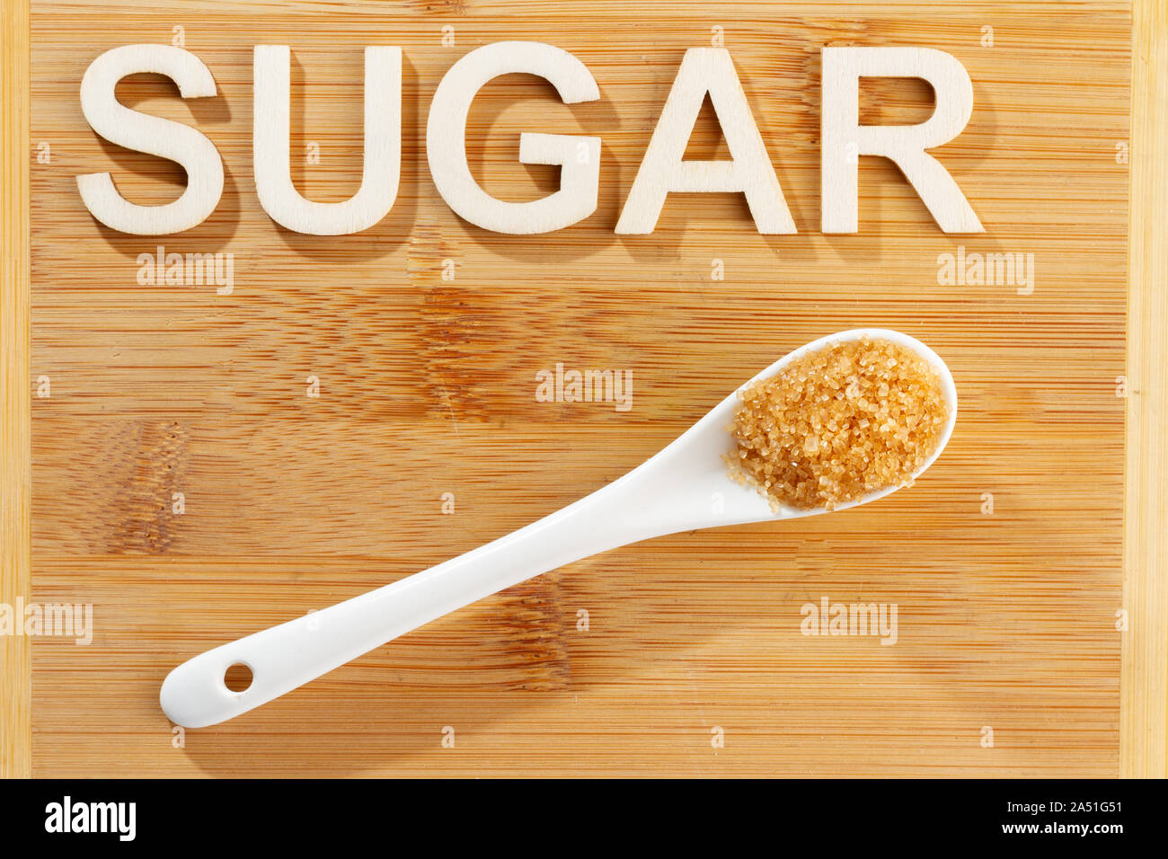 Pile of cane sugar on wooden background, word sugar Stock Photo - Alamy