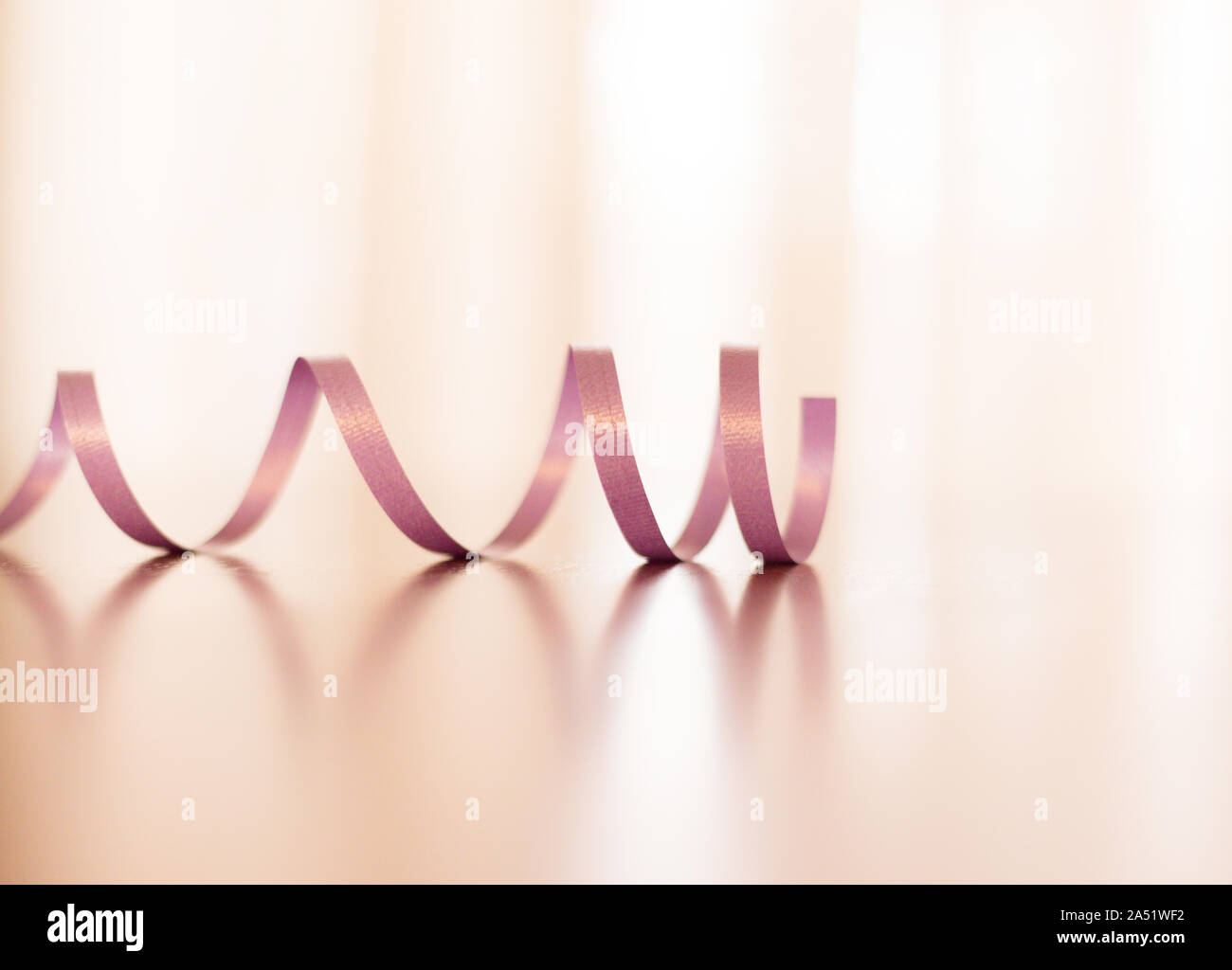 Birthday ribbon curling across a table with a bright background Stock ...