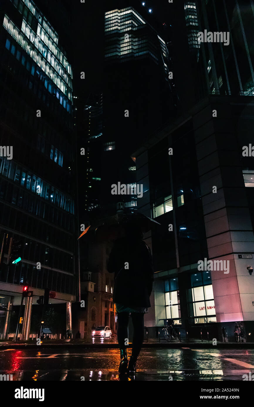 woman standing under the rain in front of high business office ...