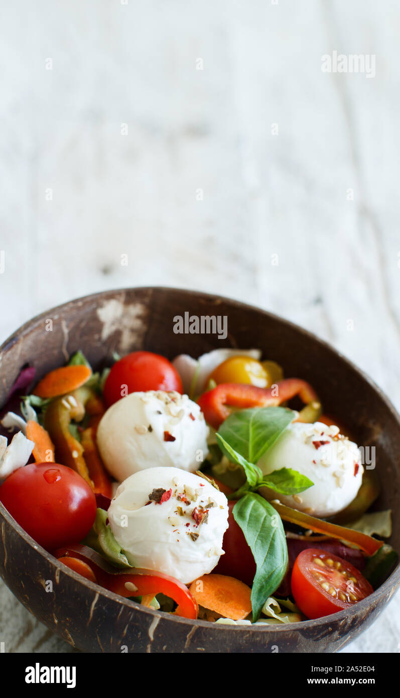 Mixed salad with mozzarella in coconut bowl close up Stock Photo - Alamy