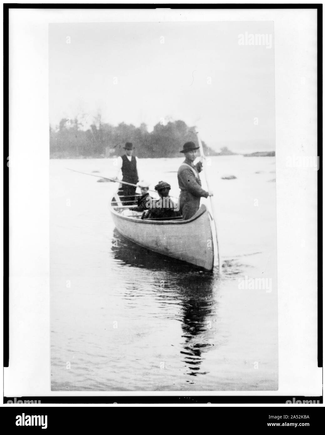 Two Indian guides standing, and two women seated, in canoe, in the ...