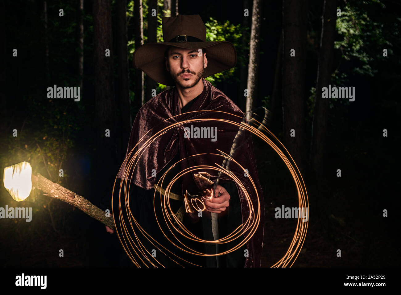 Young man in halloween cosplay holding a magic staff and swinging a ...