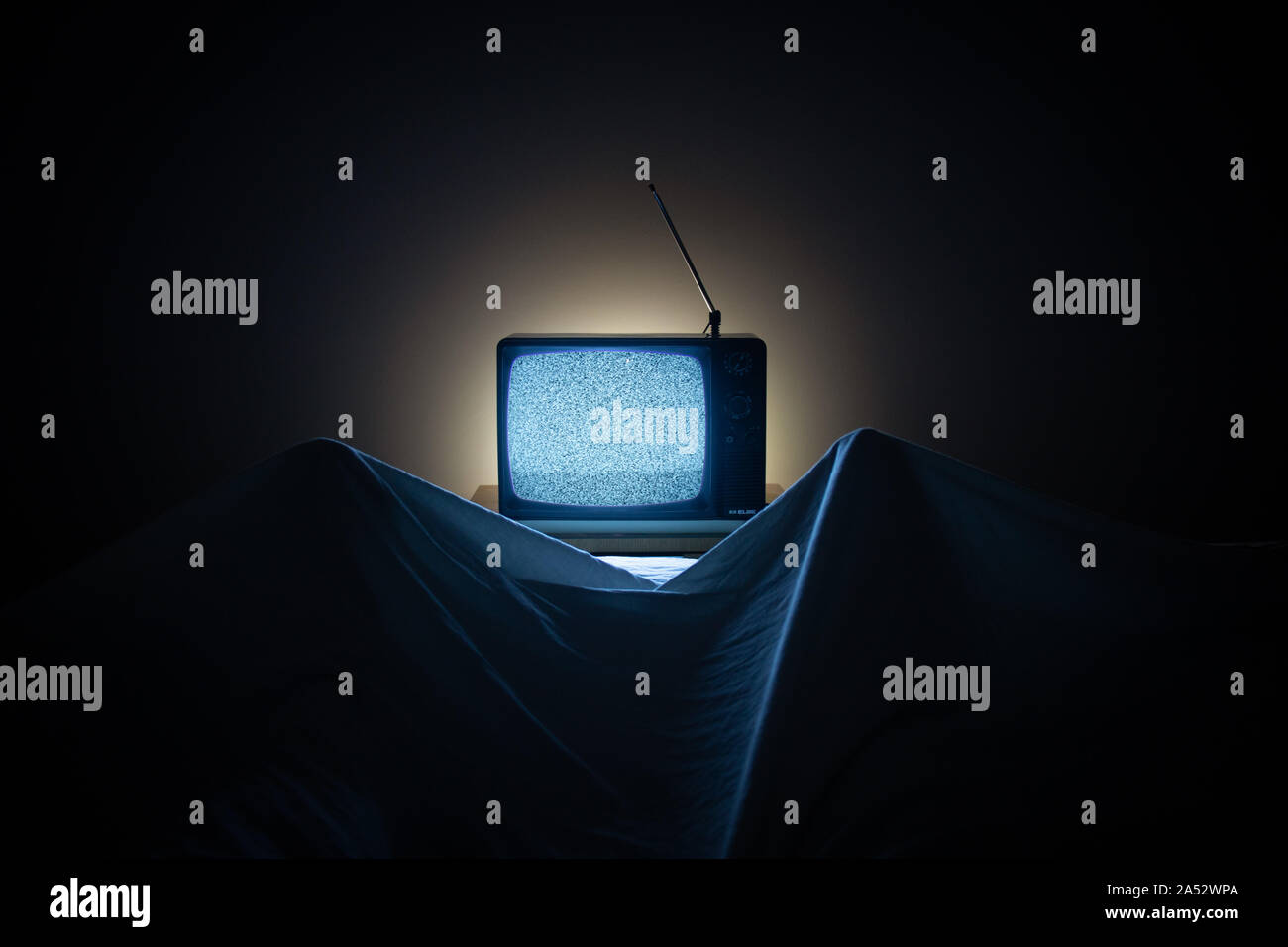 One person watches TV at night in his bed with his feet bellow of the ...