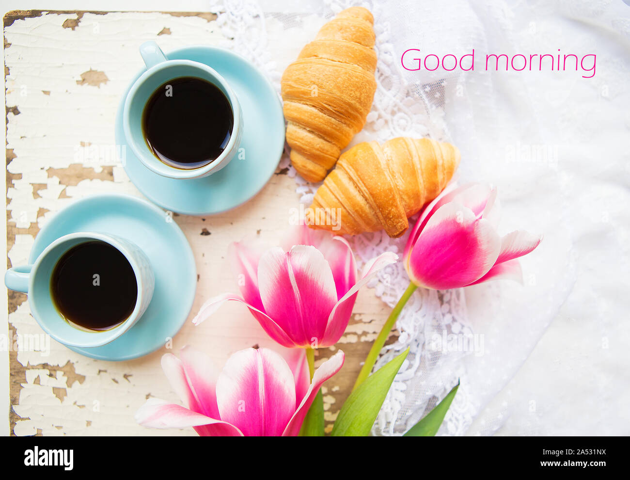 nice cup of coffee, croissants and pink tulips on old white table ...
