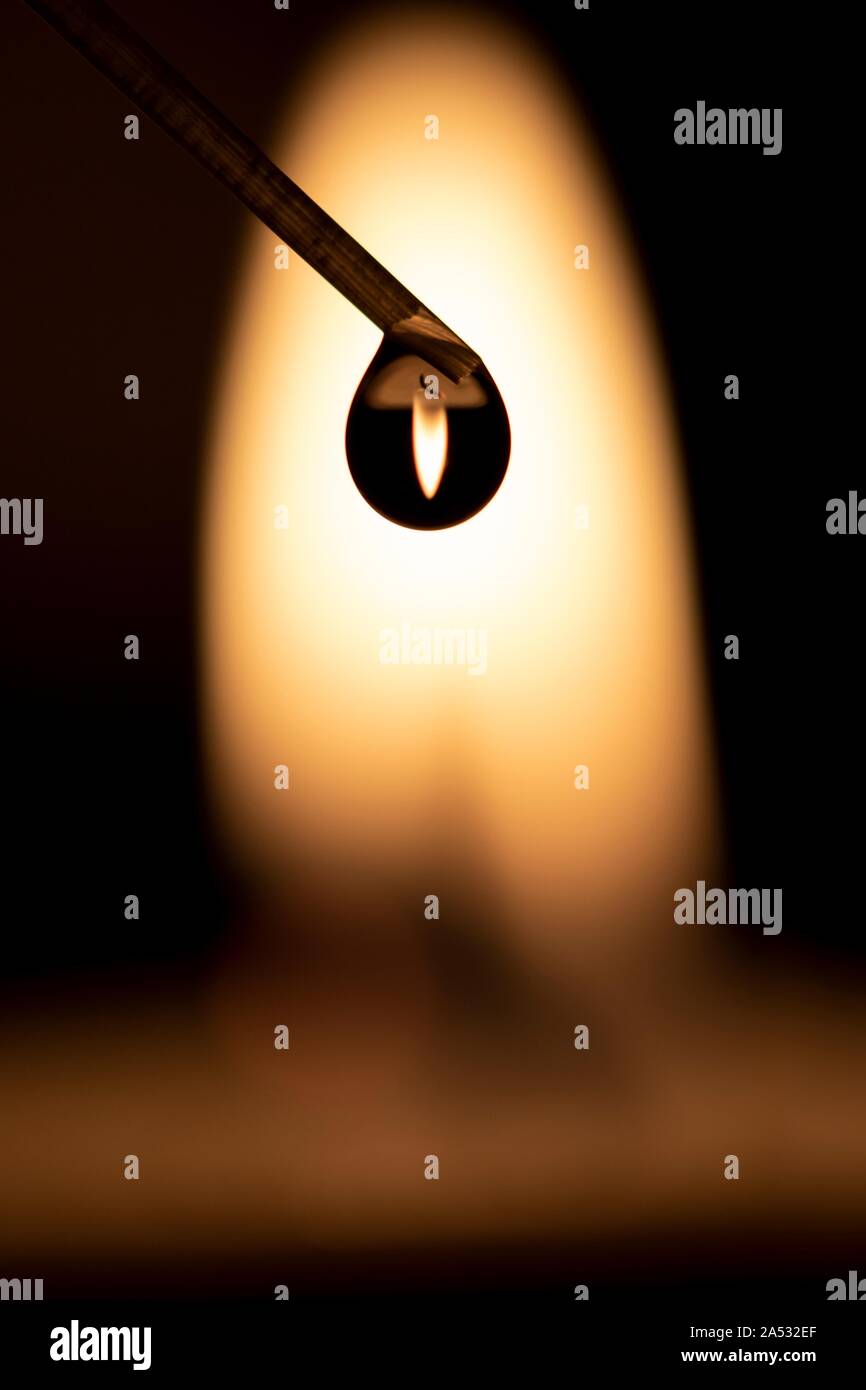 A macro portrait of a water droplet in front of a flame. The flame ...