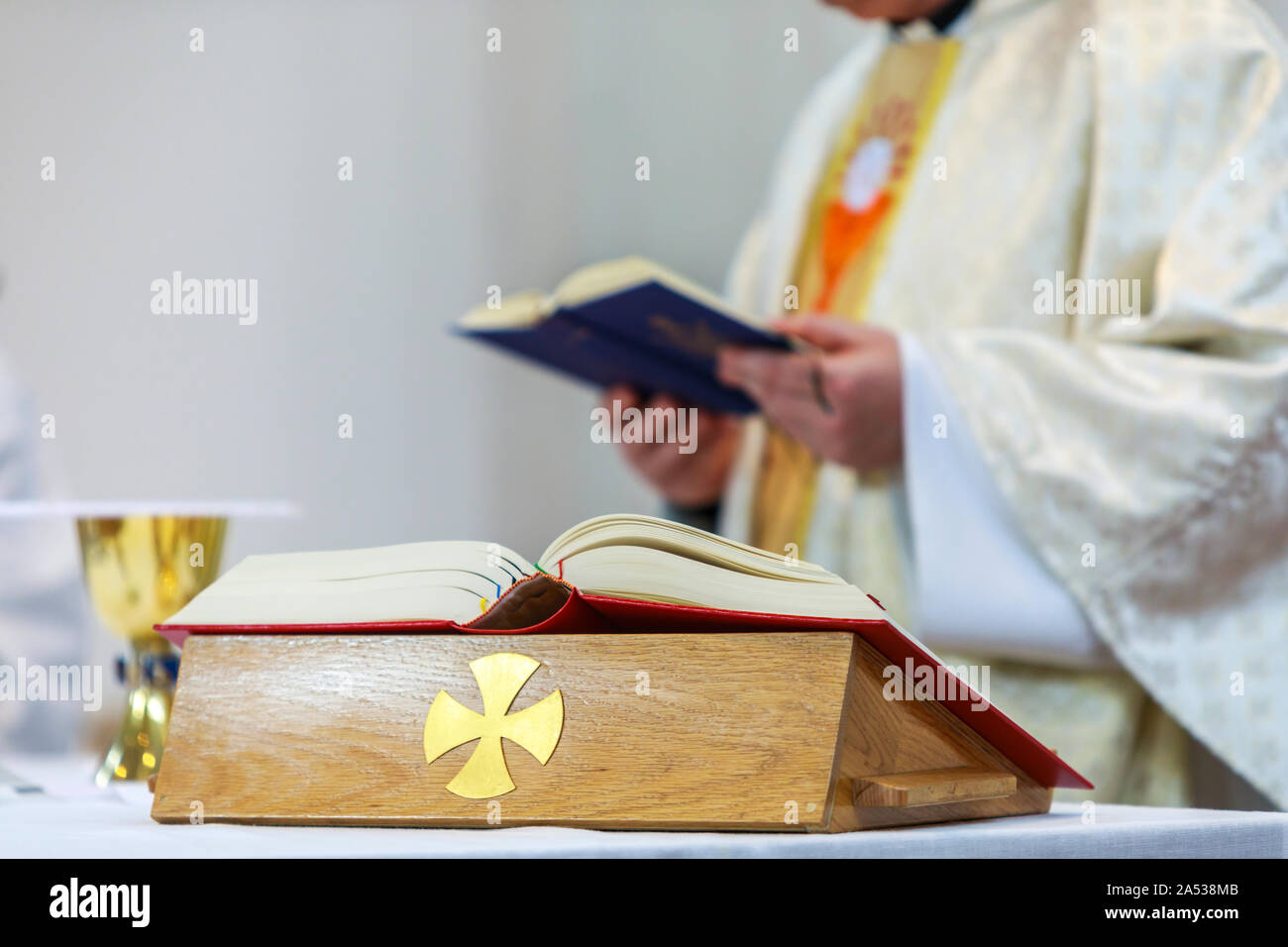 A bible on a table with a blurred unidentifiable man in a ceremonial ...