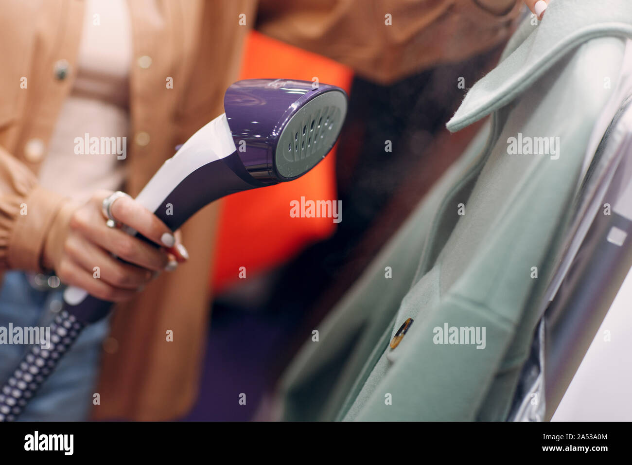 Woman steaming coat with a steamer Stock Photo - Alamy