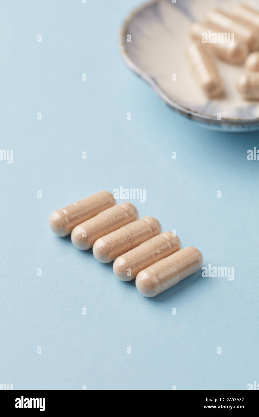 Ashwagandha (Withania somnifera) capsules. Blue paper background. Close ...