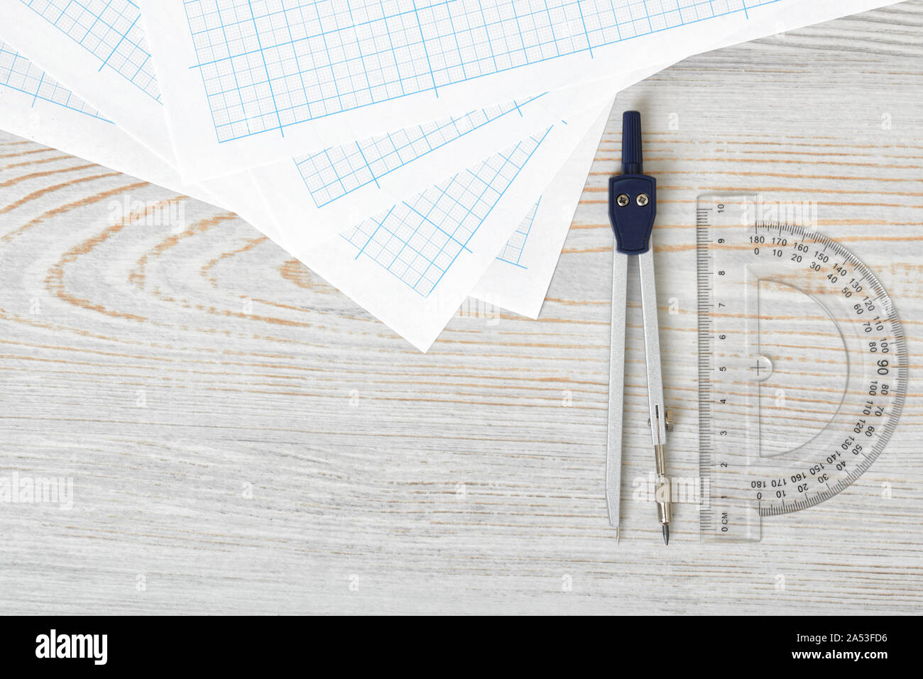 Layout with compass, protractor and graph paper on wooden surface in ...