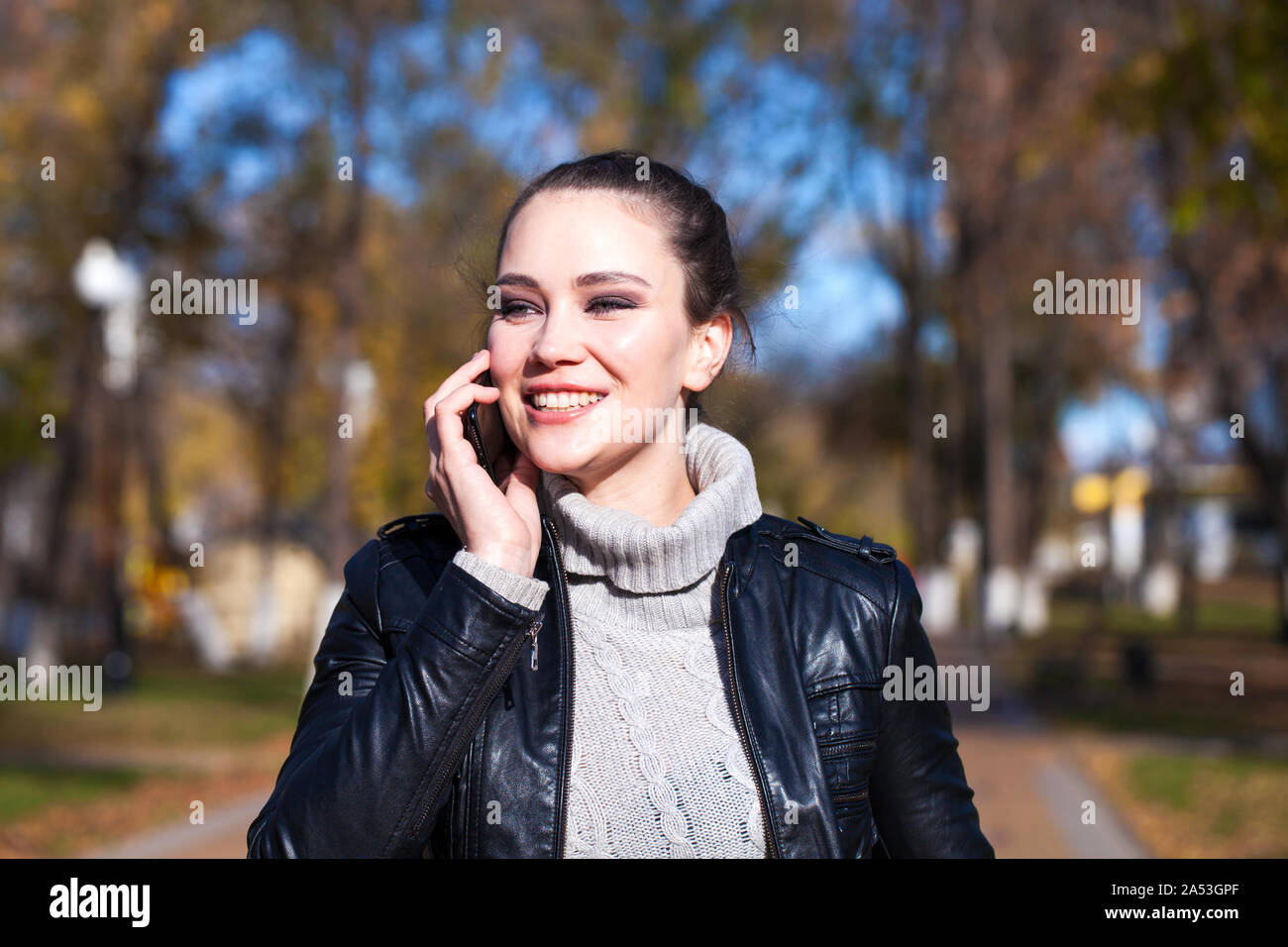 Calling by phone happy woman. Portrait of a young beautiful brunette ...