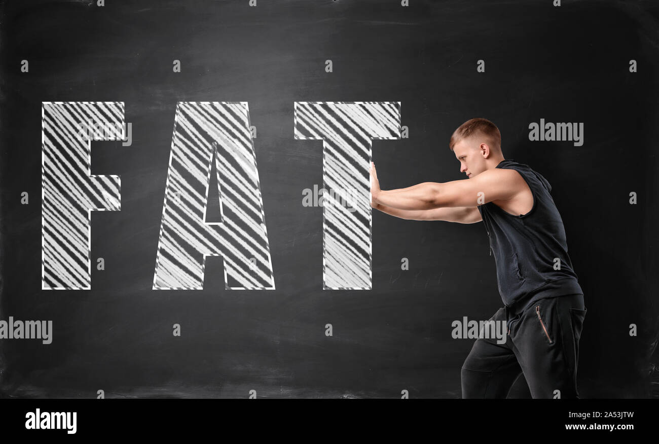 Muscled young man pushing big drawn 'fat' word by both hands on the ...