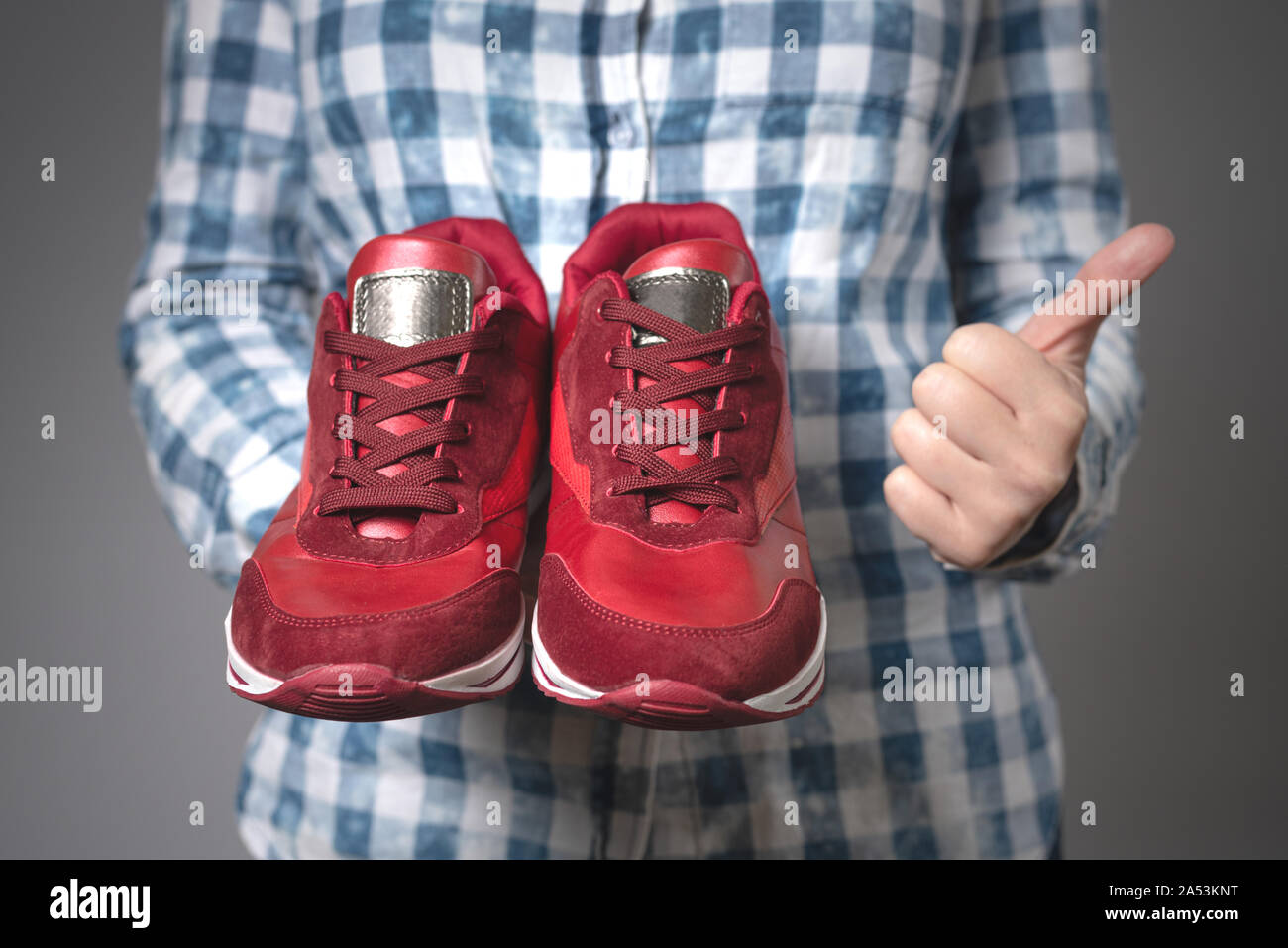 Woman with a pair of new red sport shoes in hands on gray background ...