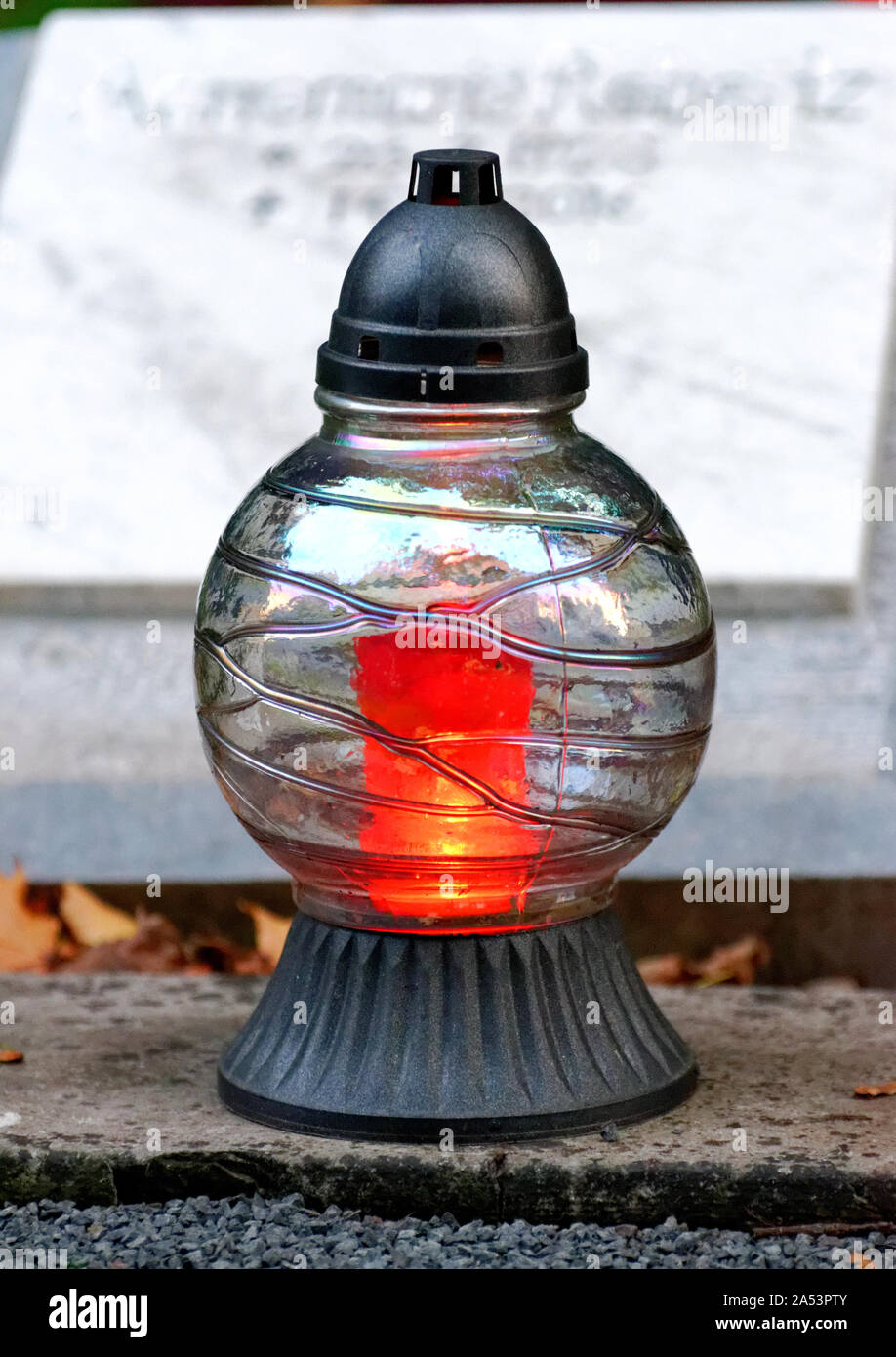 Grave light with burning candle in a cemetery, in the blurred background a gravestone Stock ...