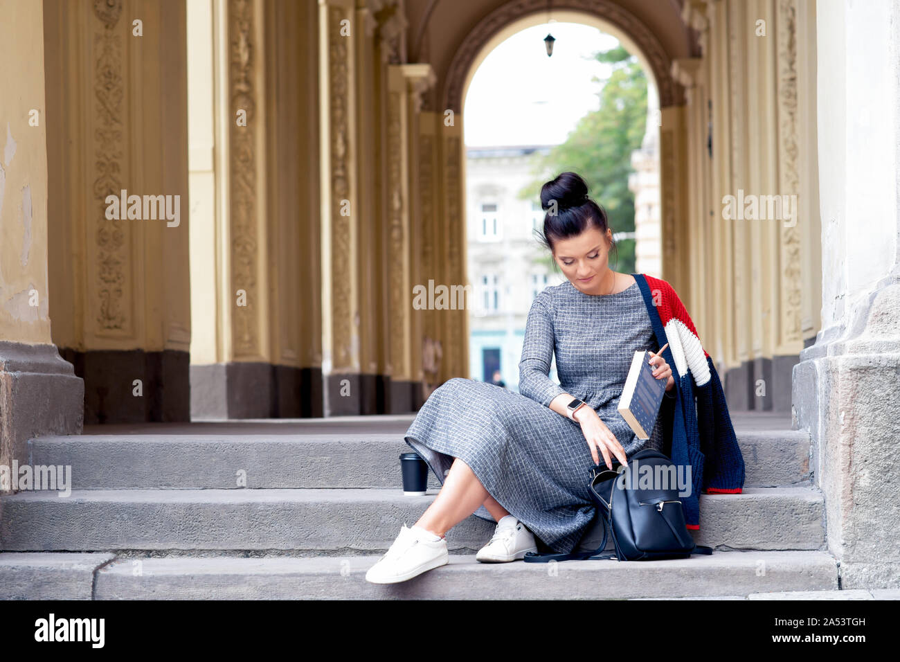 Student girl is putting the books into black backpack on stairs of ...