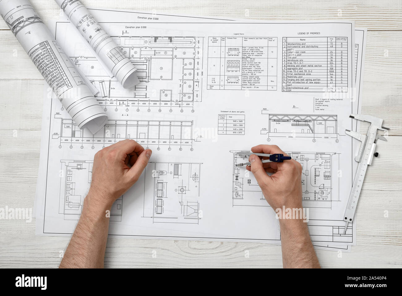 Close-up hands of man holding an engineering divider over drawing plan ...