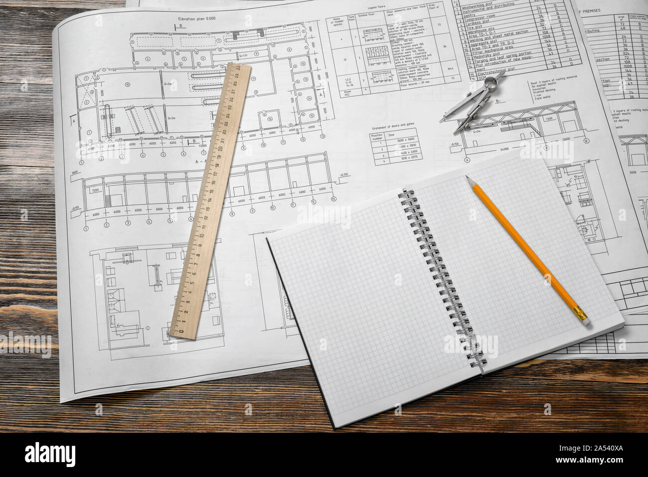 Open blueprints on wooden table background with a pencil, a ruler and ...