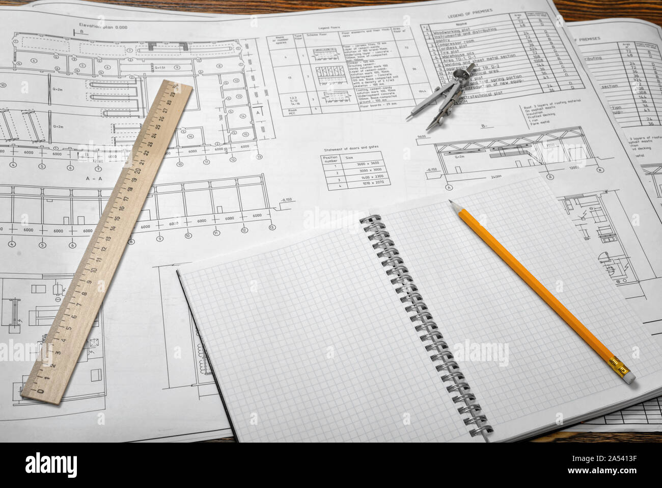 Open blueprints on wooden table background with a pencil, a ruler and ...