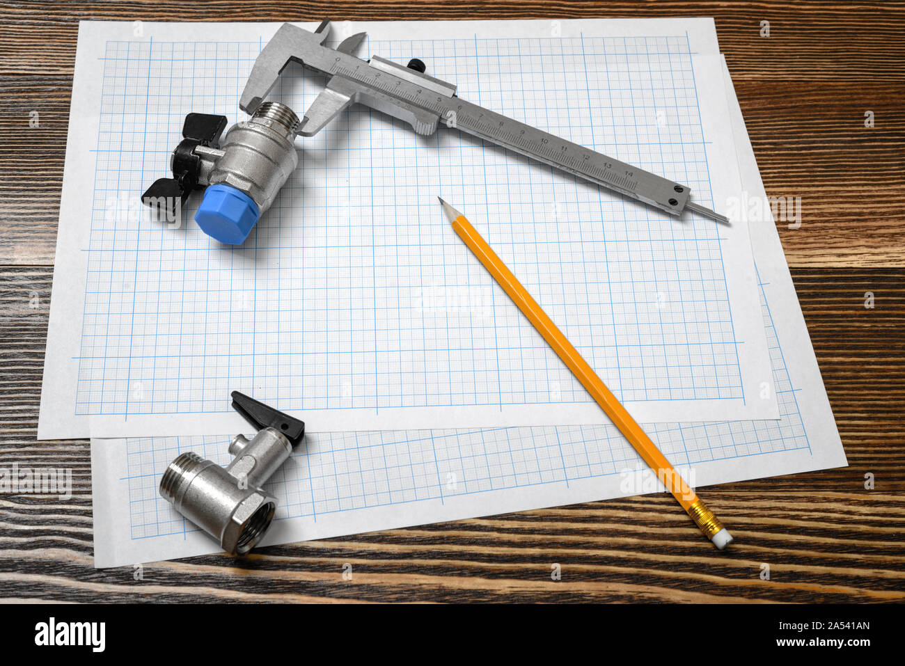 A large vernier scale lying on cross section paper with two ball valves ...