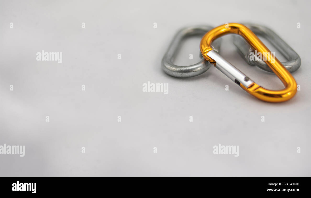 Climbing carabiners, two gray and one orange, on impure white background Stock Photo - Alamy