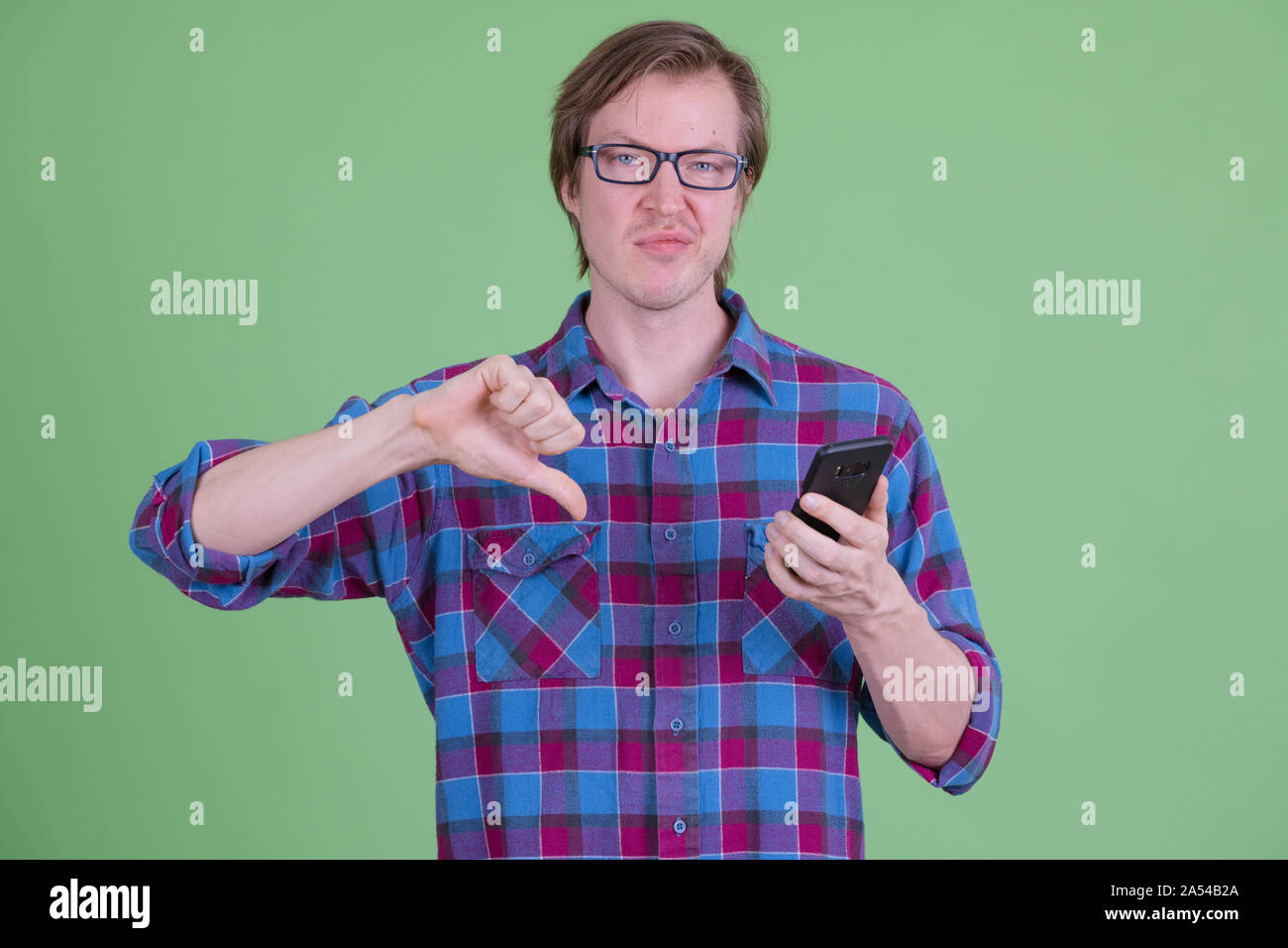 Stressed young hipster man using phone and giving thumbs down Stock ...