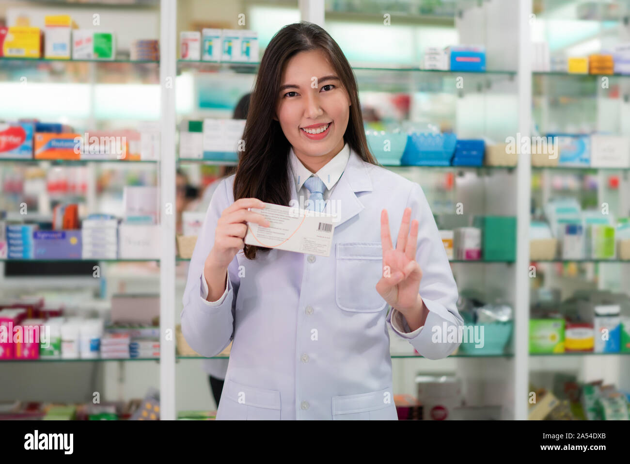 Asian young female pharmacist showing three finger explaining to her ...
