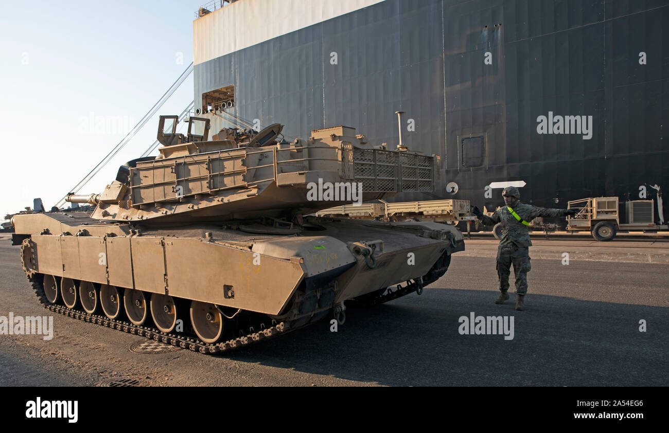 A U.S. Army Soldier ground guides an M1 Abrams after it was offloaded ...