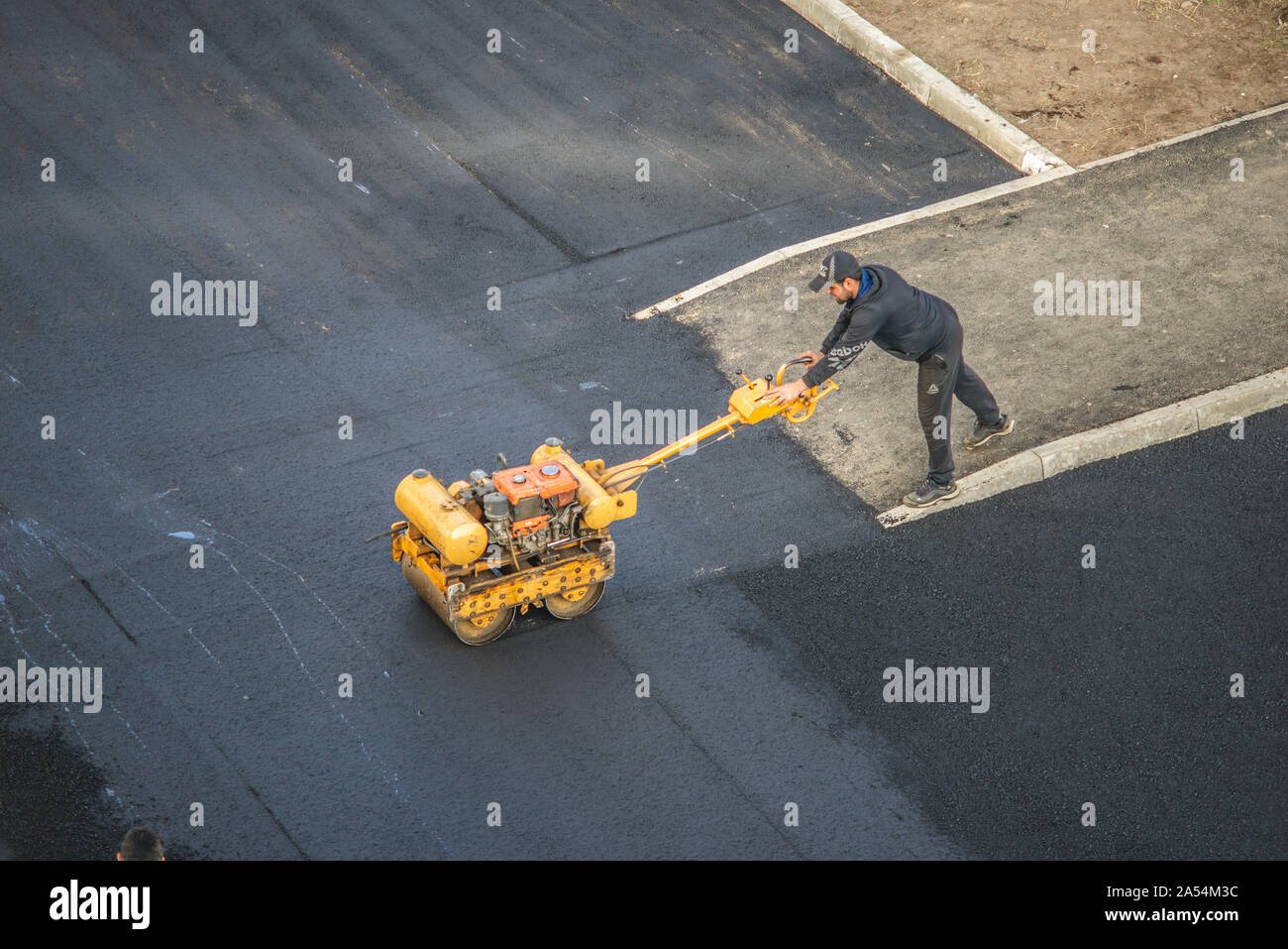 Workers lay a new asphalt coating using hot bitumen. Work of heavy ...