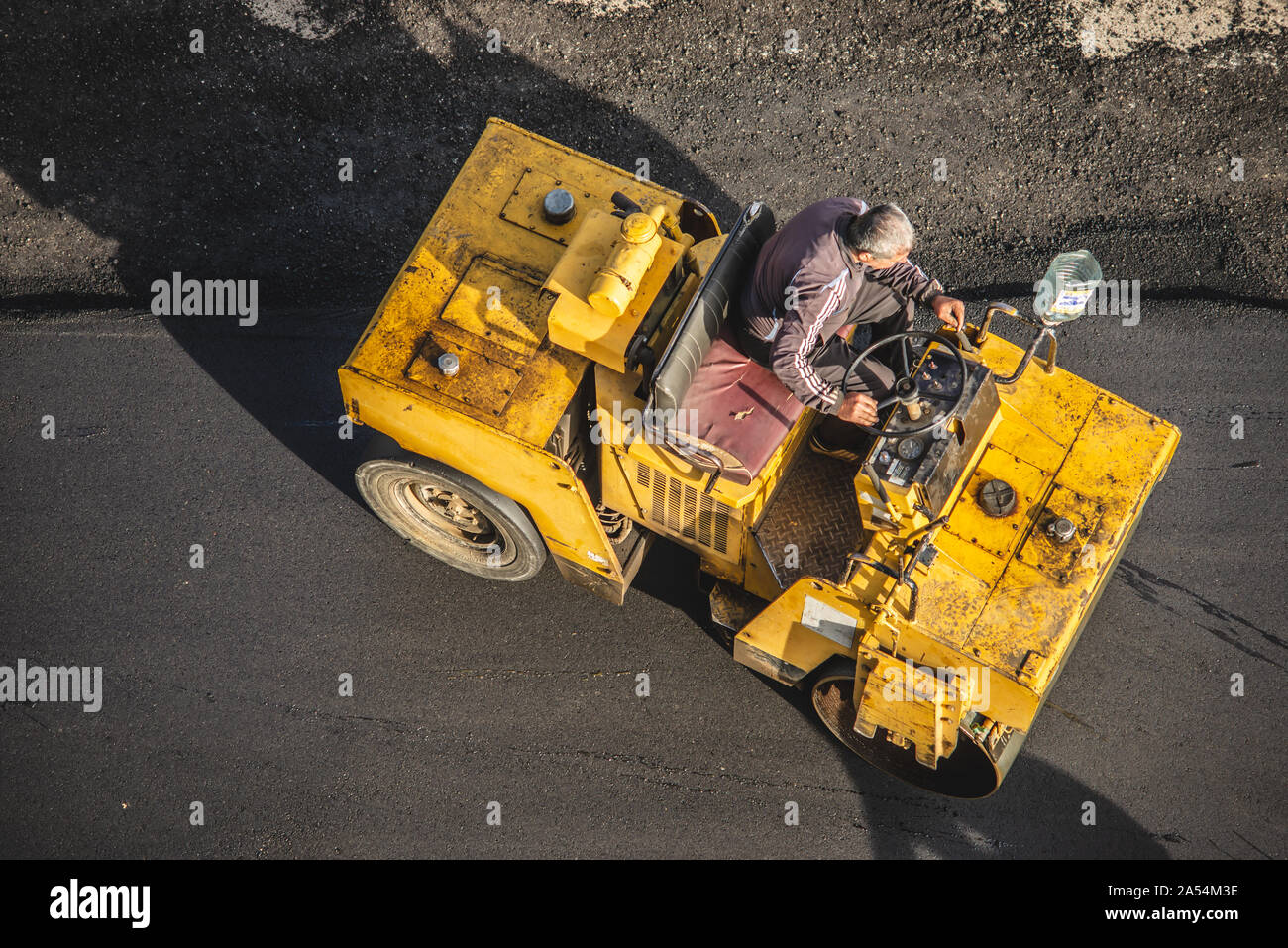 Workers lay a new asphalt coating using hot bitumen. Work of heavy ...