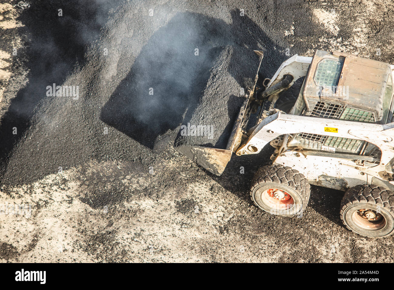 Workers lay a new asphalt coating using hot bitumen. Work of heavy ...