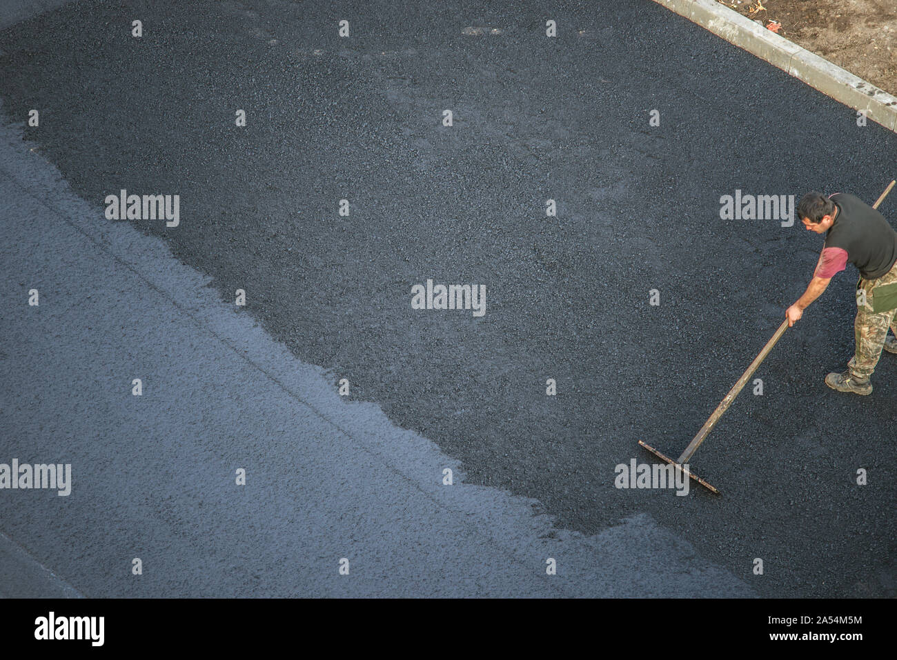 Workers lay a new asphalt coating using hot bitumen. Work of heavy ...