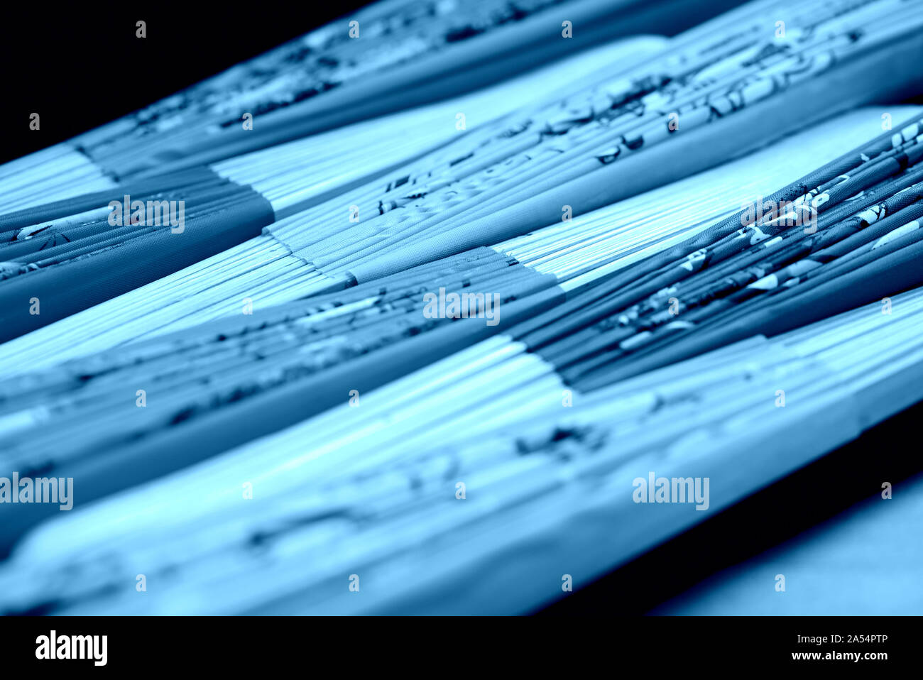 Folded Vietnamese fans on a dark background close-up. Blue color toned ...