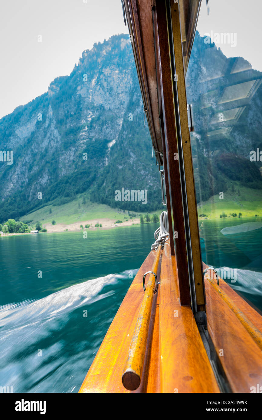 The windows of a tourist boat reflects water and mountains from the ...