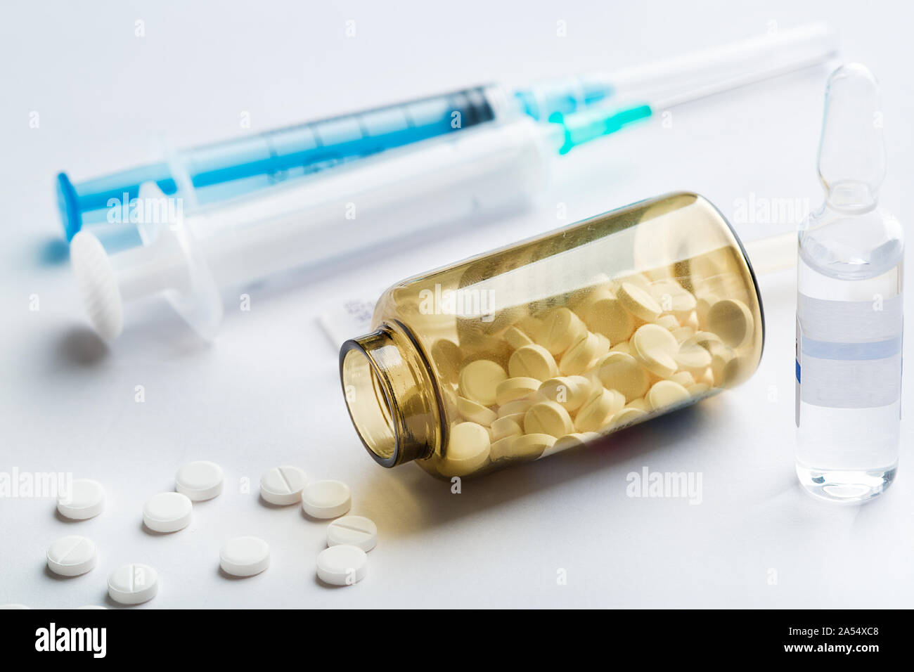 White pills dropped on white background. Syringe for injection ...