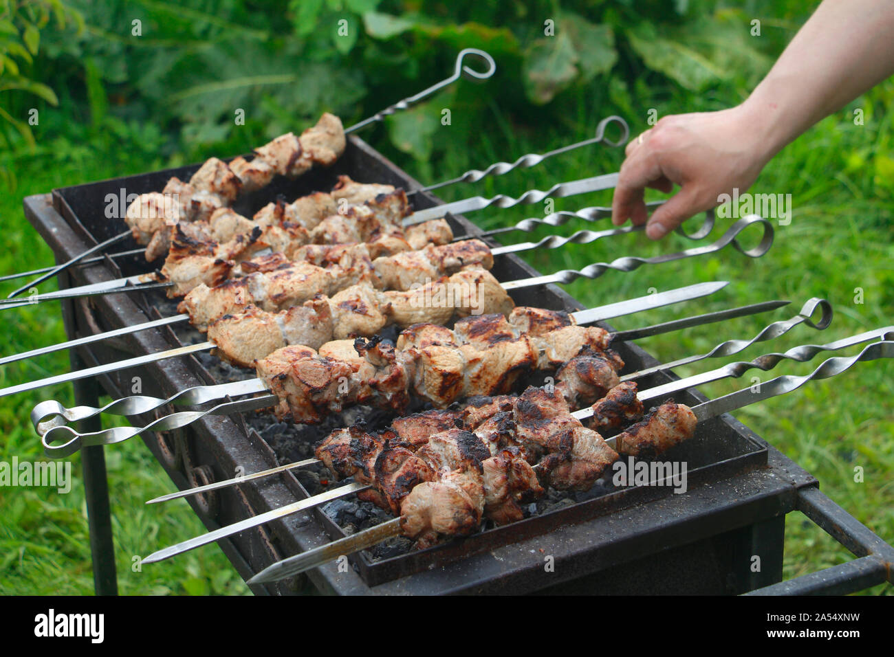 Cook cooks barbecue skewers. Marinated kebab is grilled on charcoal ...